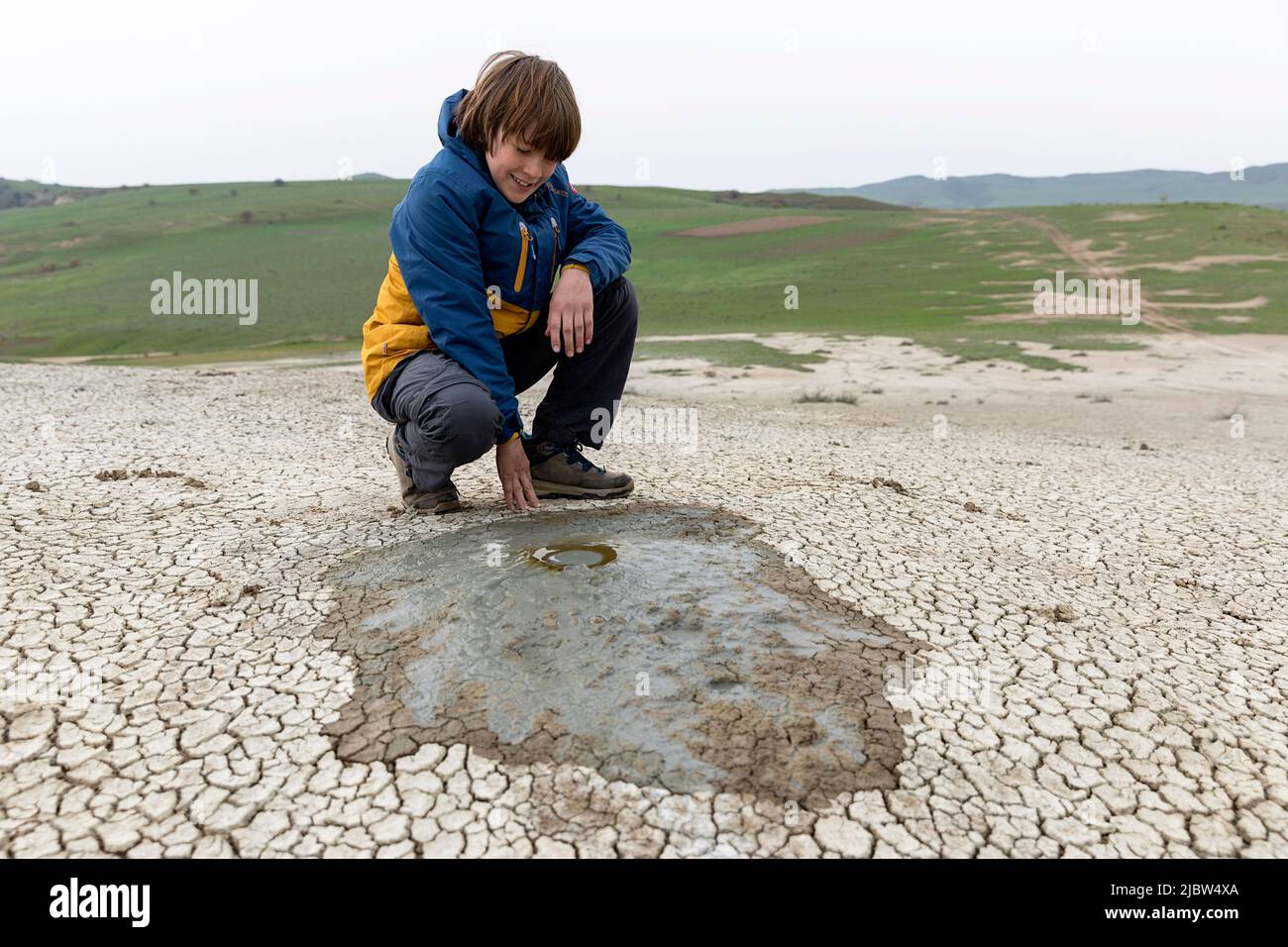 Happy boy looking at eruption of a mud volcano at Takhti-Tepha Mud ...