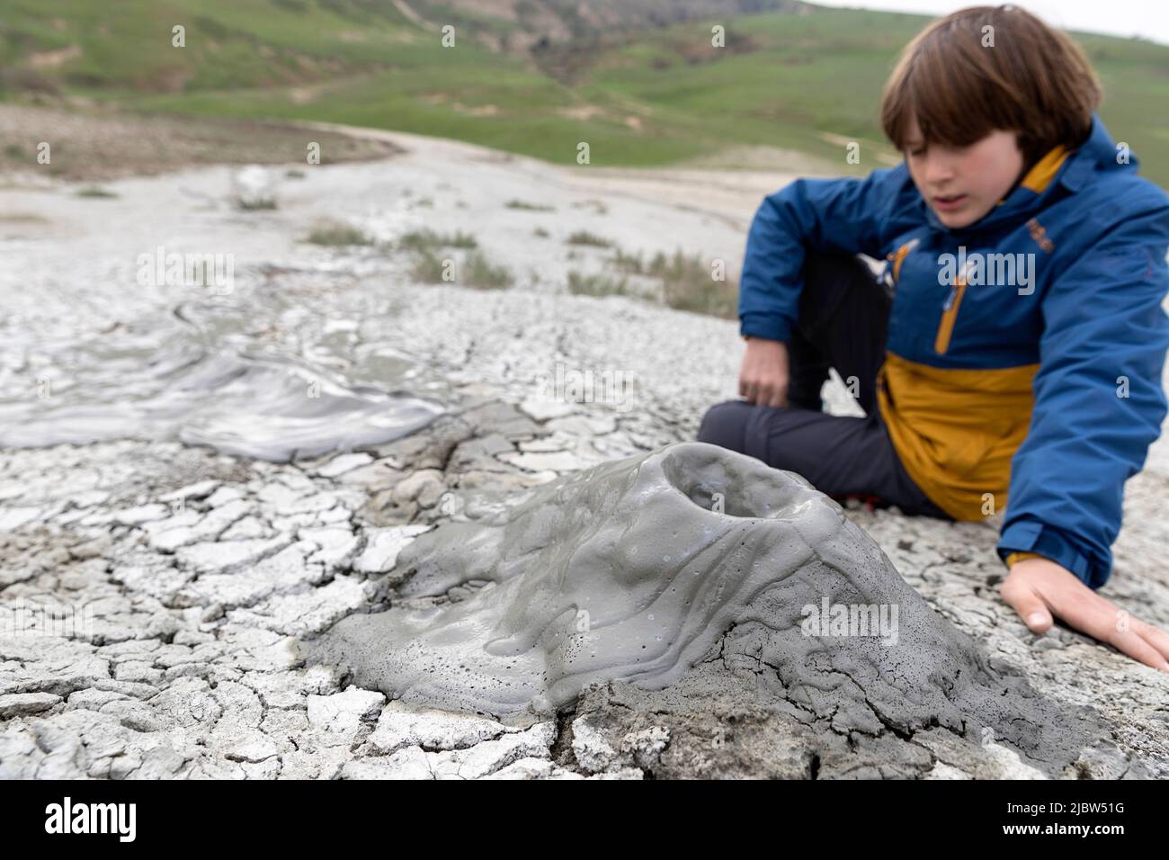Boy looking at fresh crater of a mud volcano at Takhti-Tepha Mud ...