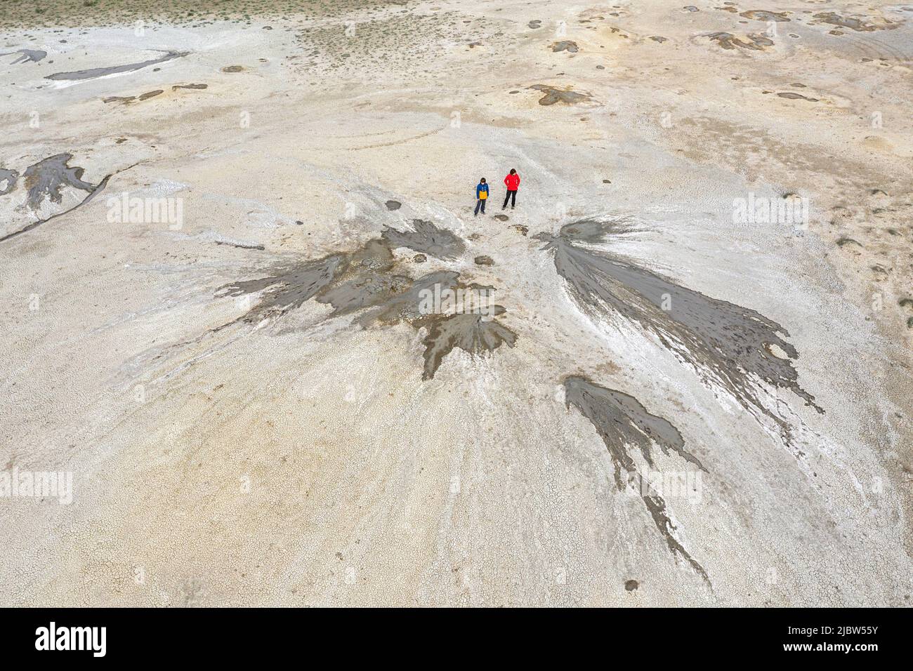 Aerial view of mother and son standing at craters of mud volcanoes at ...