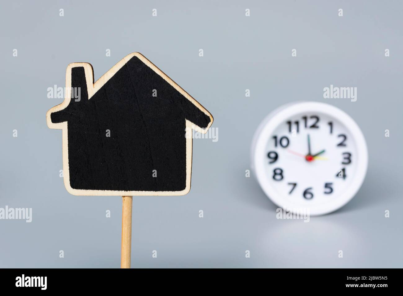 Wooden house model with blurred white alarm clock background. Real ...