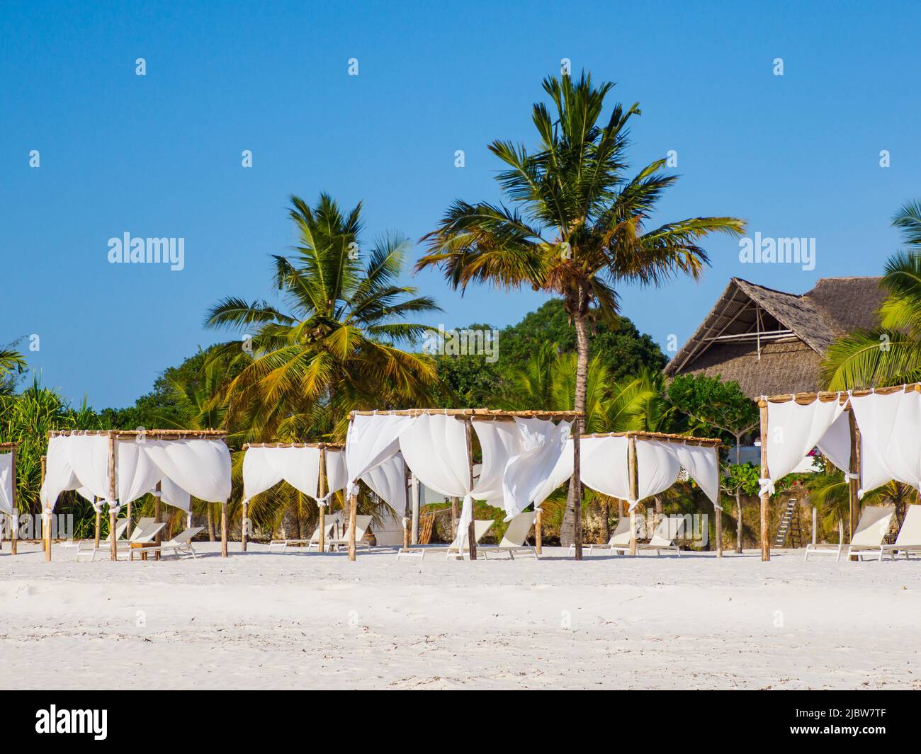 Sun loungers covered with white, airy curtains in a luxurious resort by ...