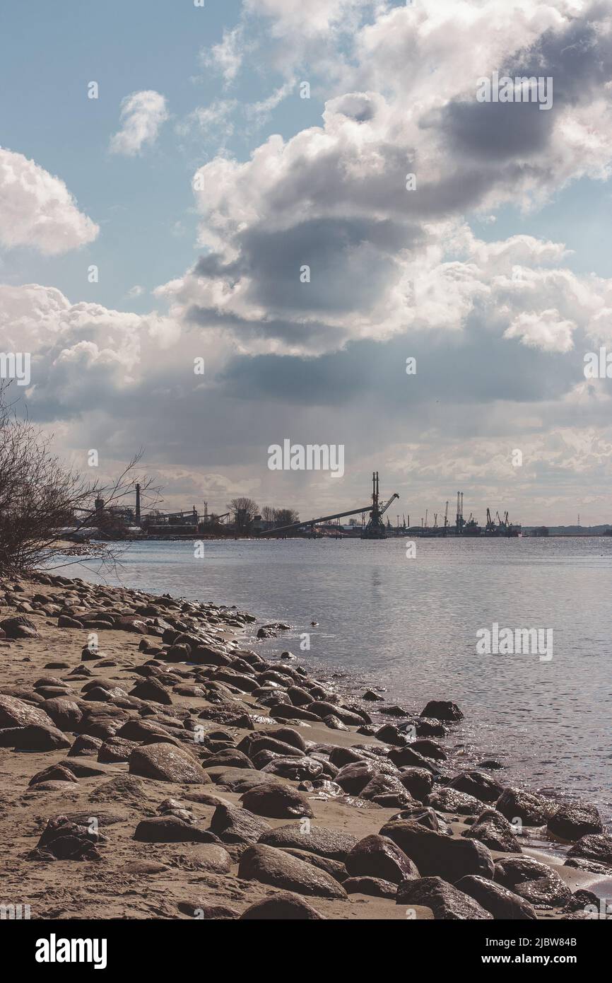 Rocky river bank landscape with a shipping port in the distance. the ...