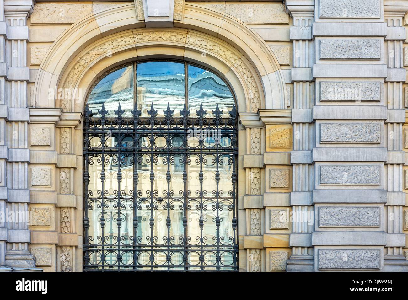Arched window with a figured iron grate against a gray-beige wall. From ...