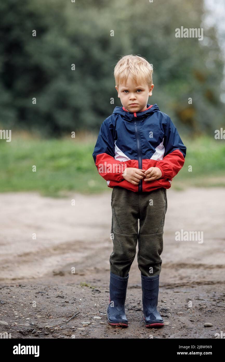 Portrait of a sad lonely boy in bad weather in autumn. The end of ...