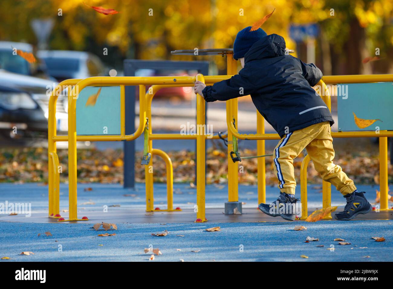 Little boy play on the playground in the park. Child spinning a yellow ...