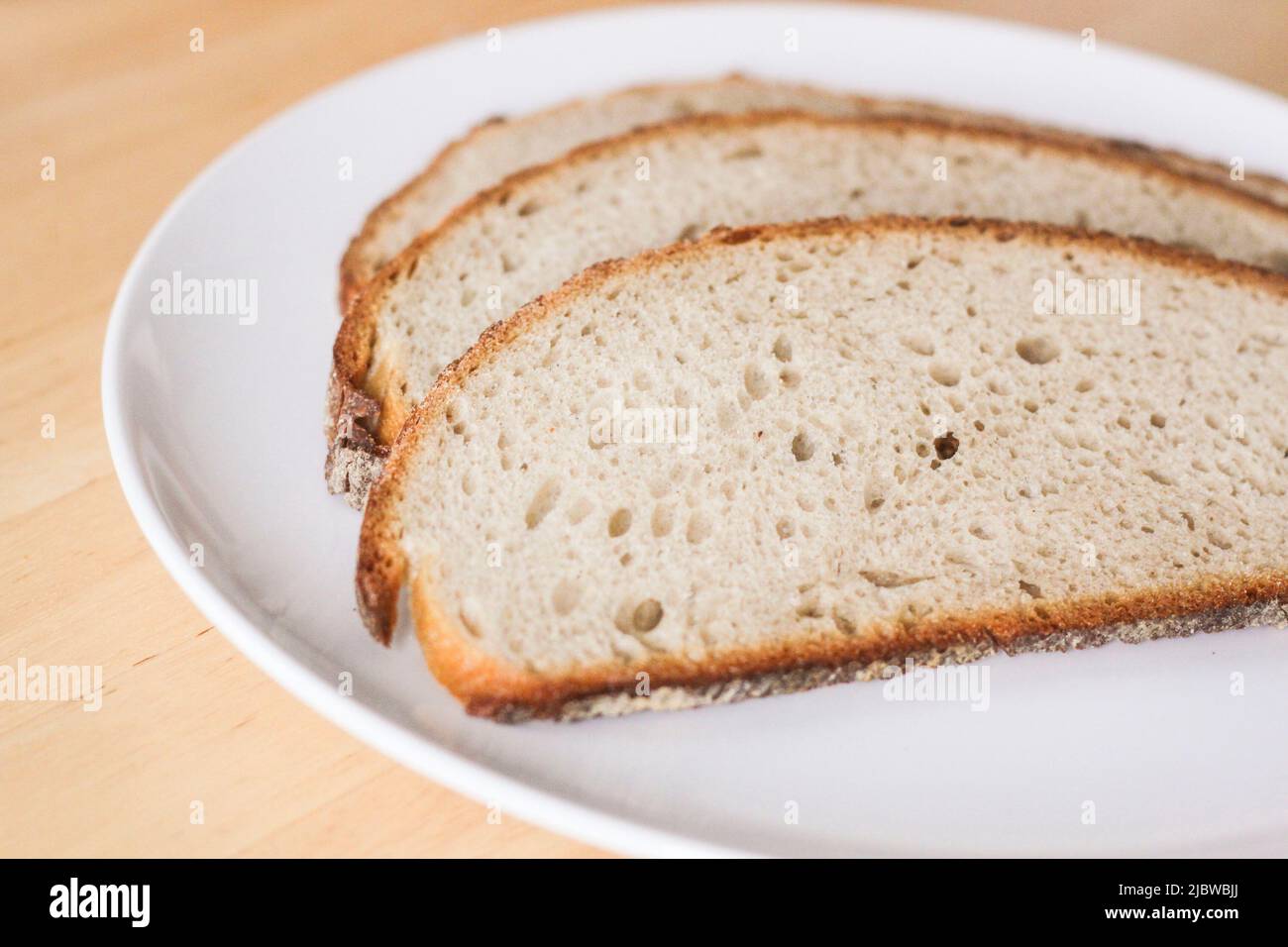Sourdough bread slices on a white platter Stock Photo - Alamy