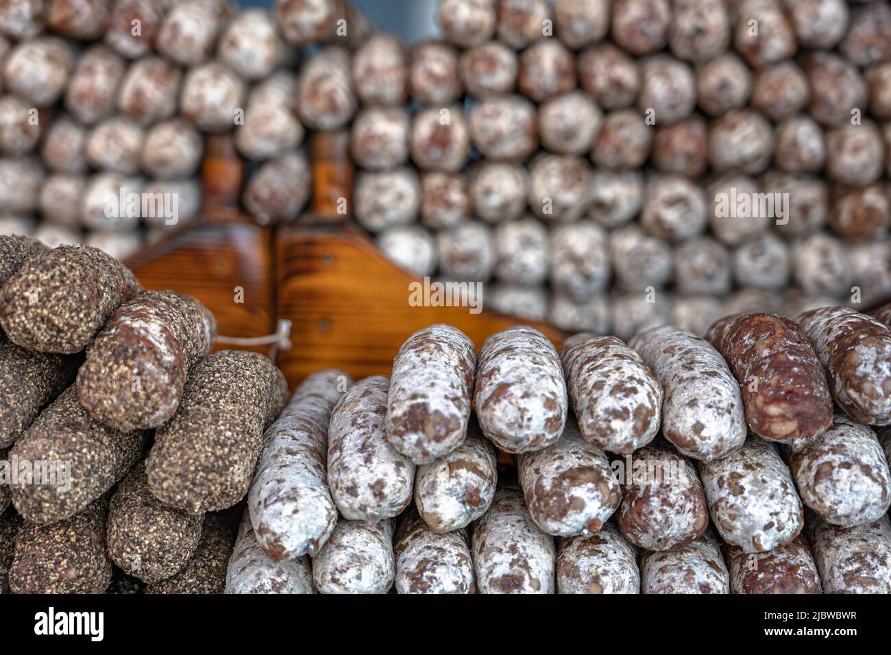 Stacks of dry-cured sausages - saucisson, typically made of pork, or a ...