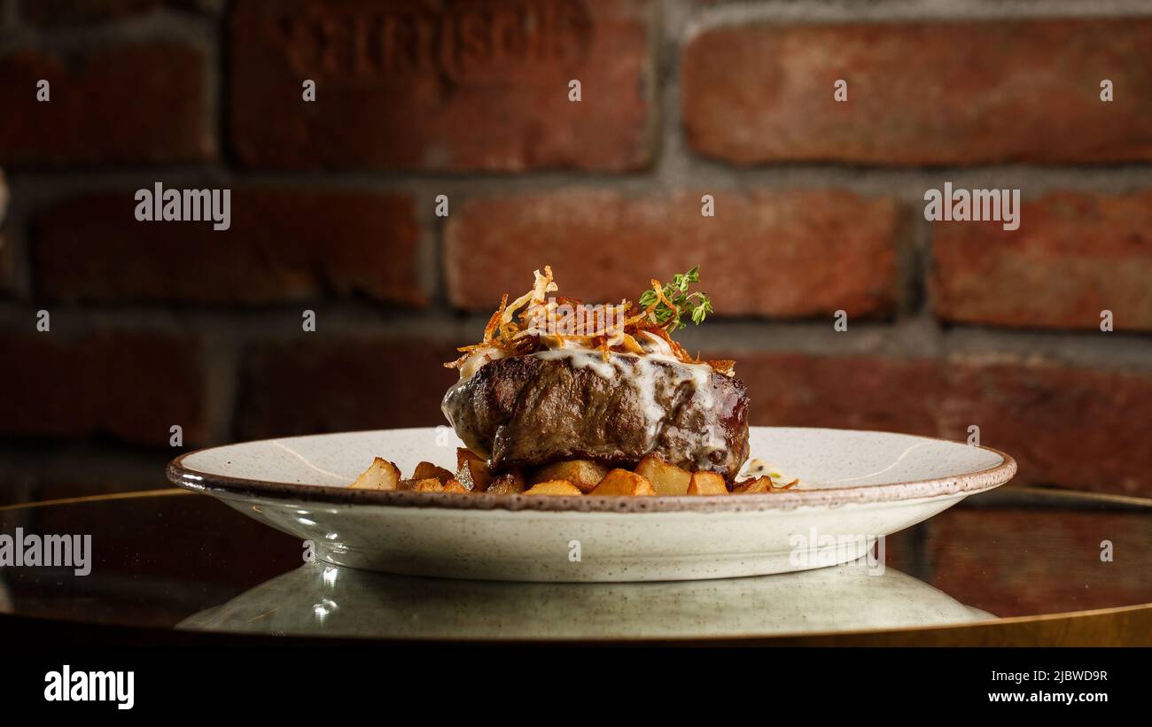 Grilled steak with baked golden potatoes served with crispy onion on ...