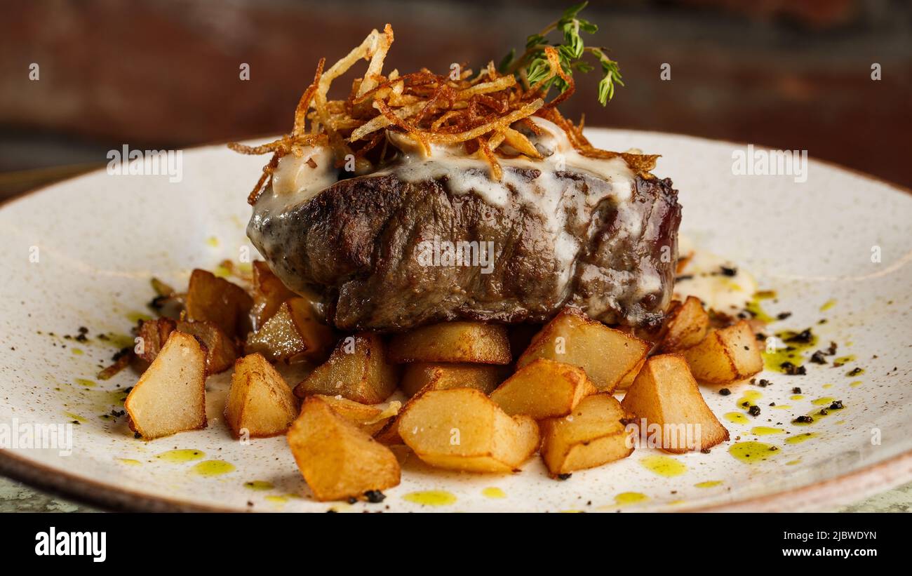 Grilled steak with baked golden potatoes served with crispy onion on ...