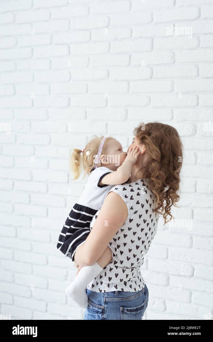 Mother holds her child with hearing aids and cochlear implants on white ...