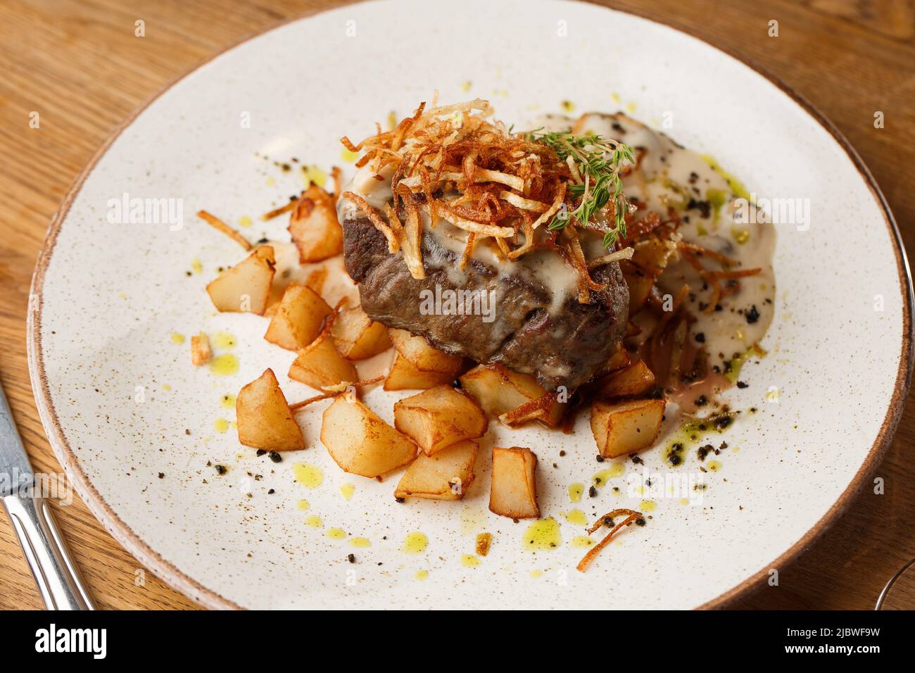 Grilled steak with baked golden potatoes served with crispy onion on ...