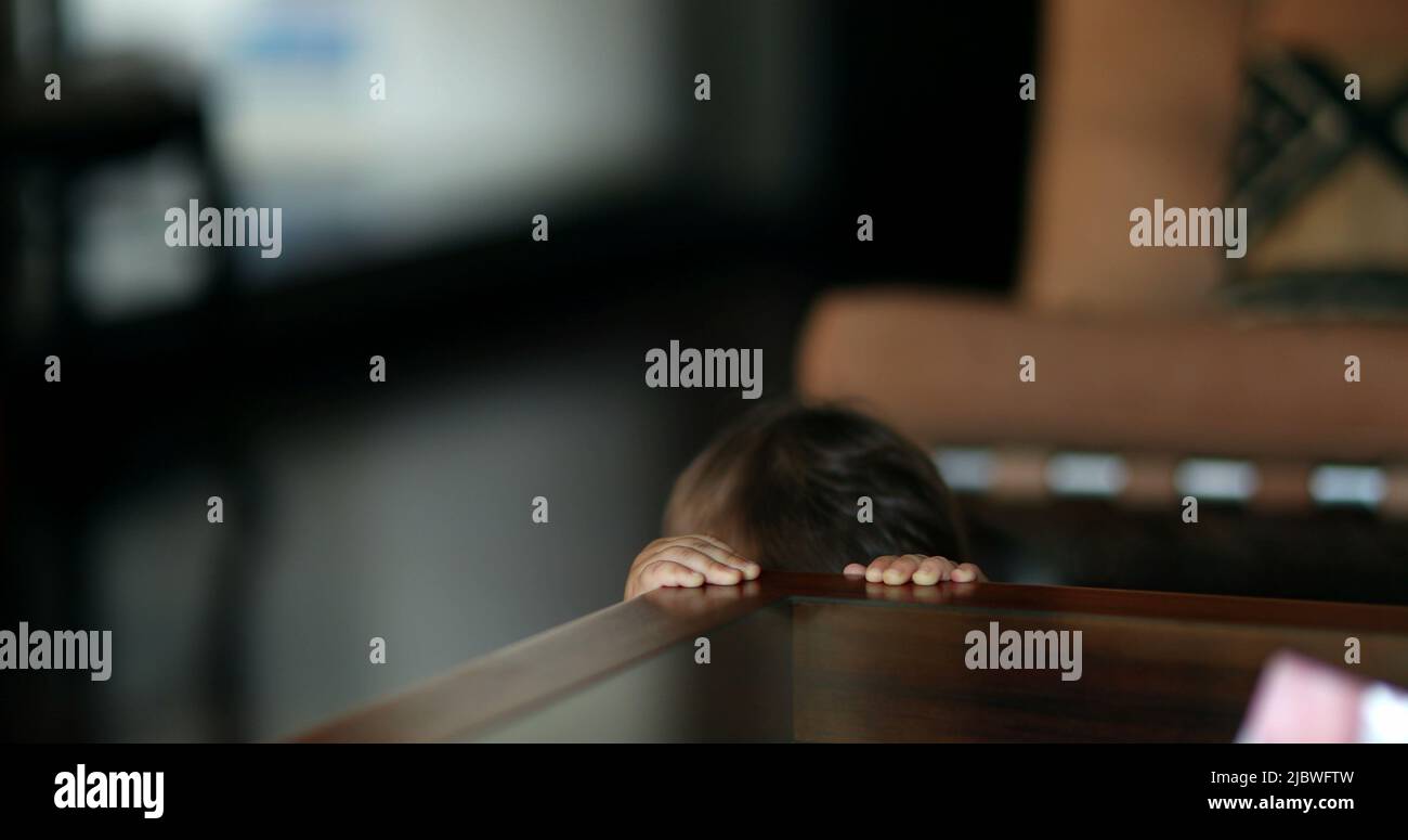 Adorable baby hiding under table. Infant boy smiling to camera portrait ...
