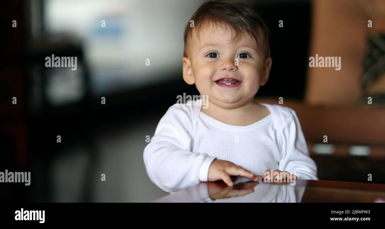 Adorable baby hiding under table. Infant boy smiling to camera portrait ...