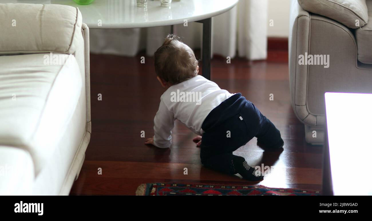 Baby learning to stand. Infant standing up holding into table furniture ...
