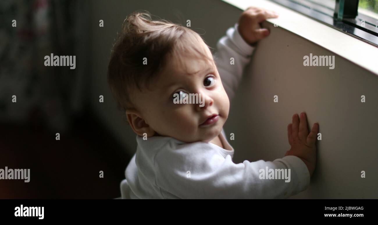 Baby next to home window looking outside. Infant boy leaning window ...