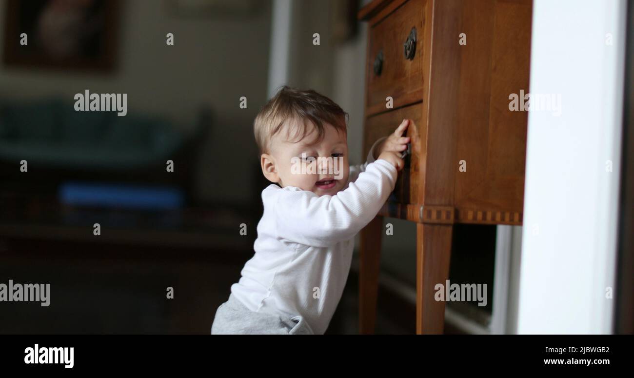 Baby learning to stand by holding into home furniture. Infant toddler ...