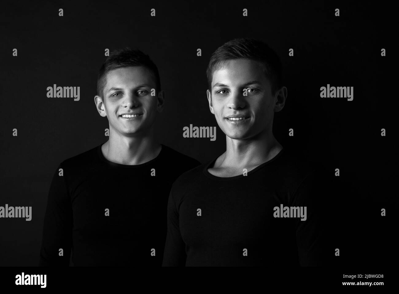Two attractive positive young twin brothers standing dressed in Stock ...