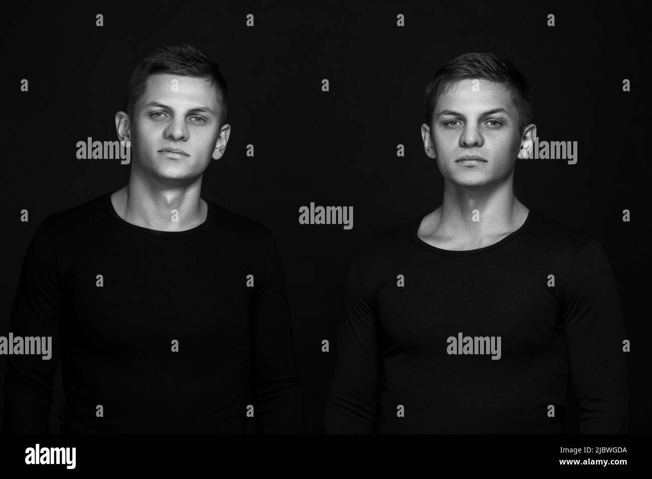 Two attractive positive young twin brothers standing dressed in Stock ...