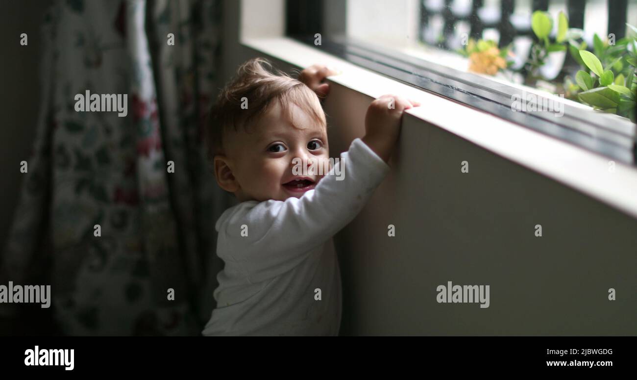 Baby next to home window looking outside. Infant boy leaning window ...