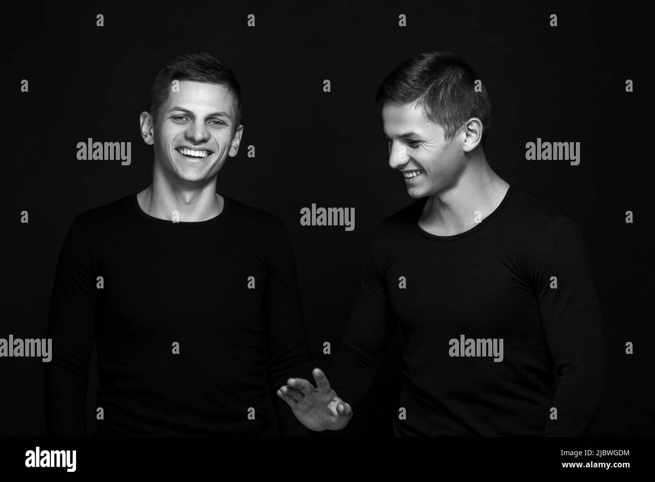 Two attractive positive young twin brothers standing dressed in Stock ...