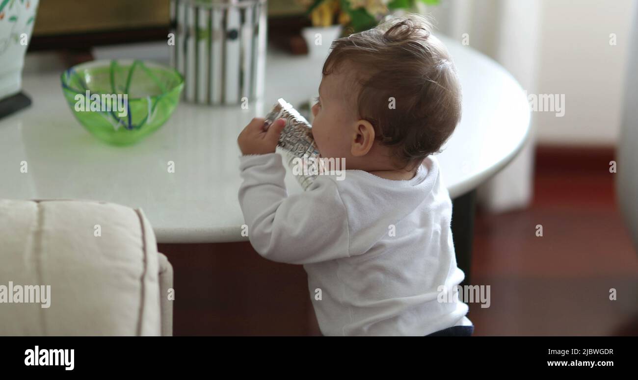 Baby standing up at home holding objects and falling down on floor ...