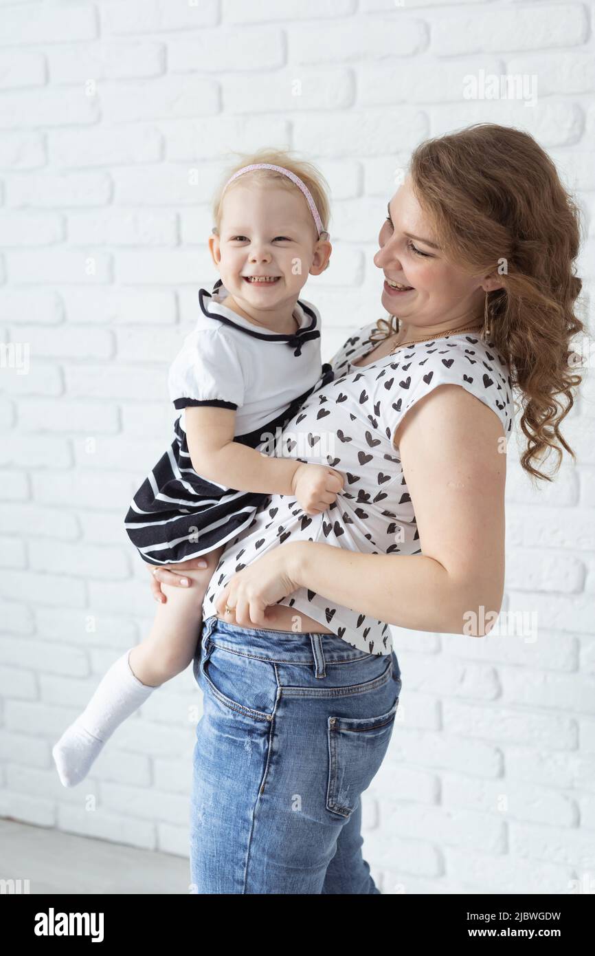 Mother holds her child with hearing aids and cochlear implants on white ...