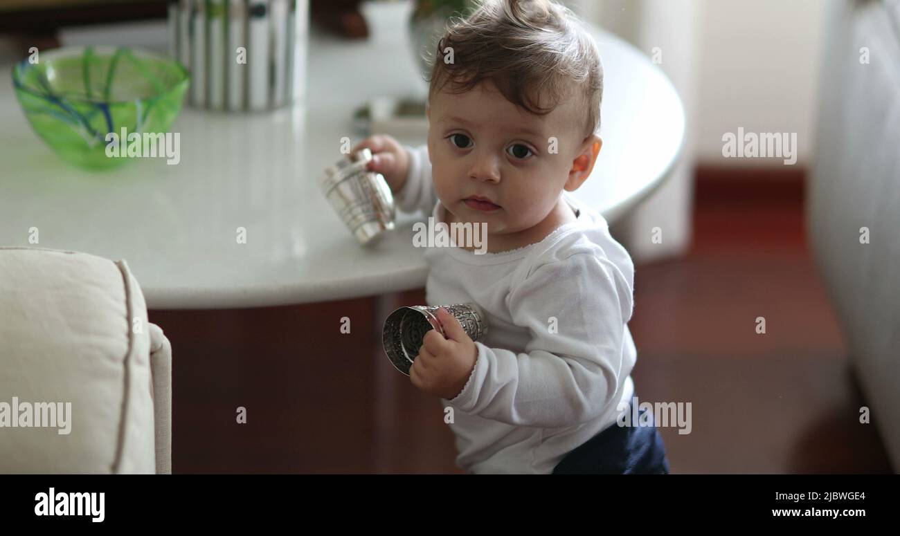 Baby standing up at home holding objects and falling down on floor ...