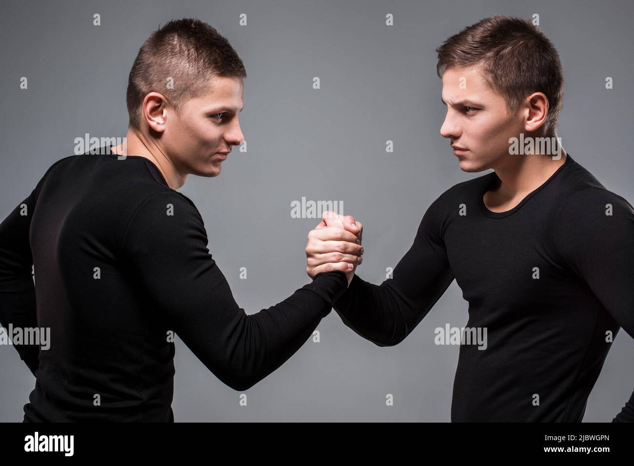 Portrait of young twin brothers standing face to face on gray ba Stock ...