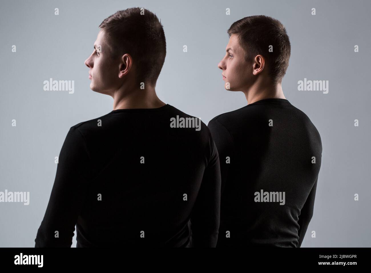The two twin brother stand with their backs on the gray backgrou Stock ...