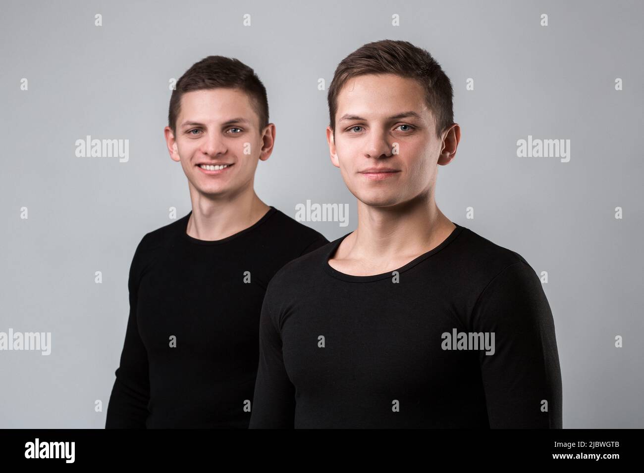 The two twin brother stand on the gray background Stock Photo - Alamy