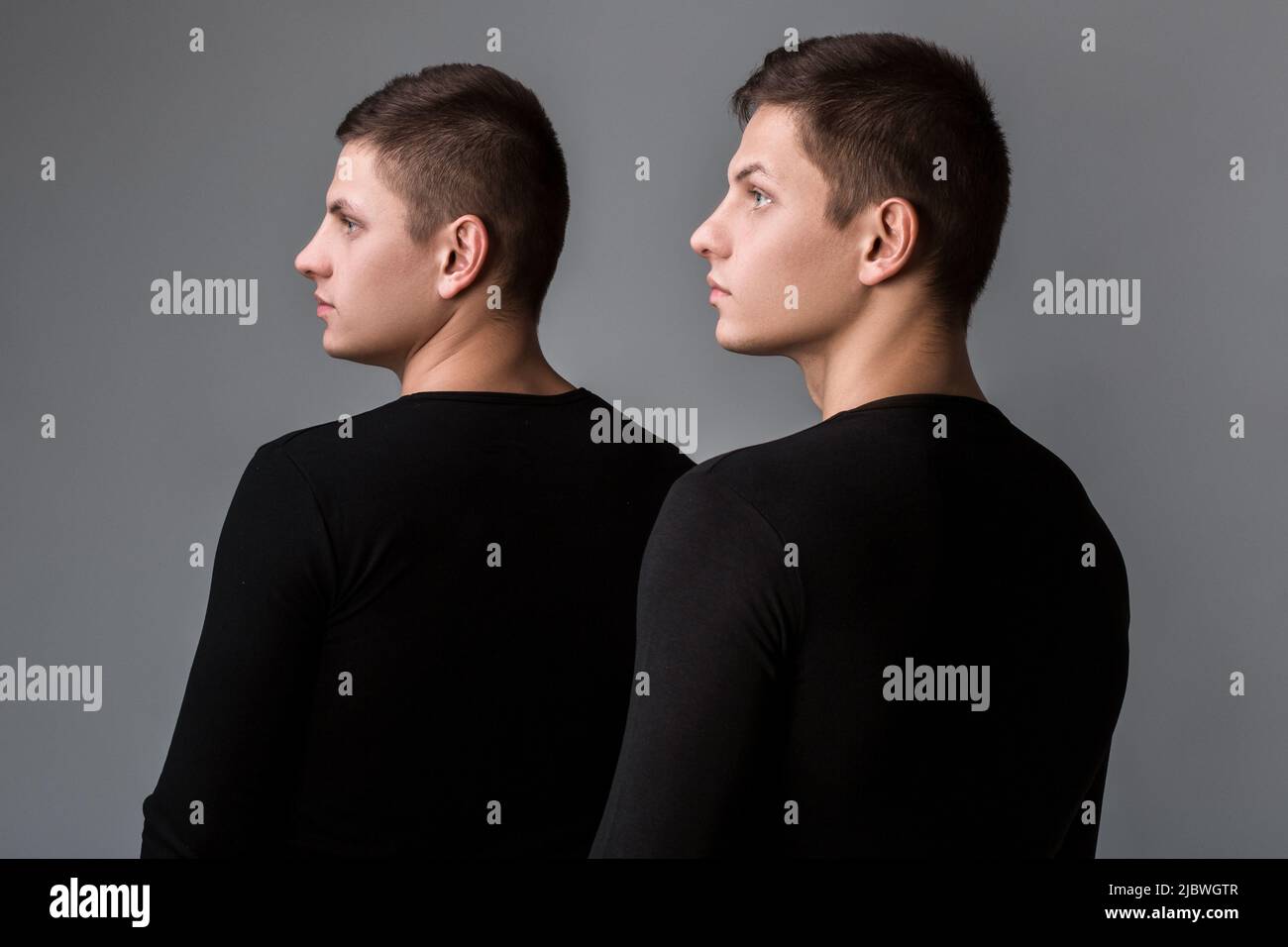 The two twin brother stand with their backs on the gray backgrou Stock ...