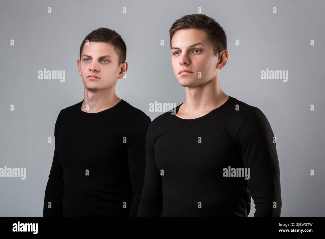 The two twin brother stand on the gray background Stock Photo - Alamy
