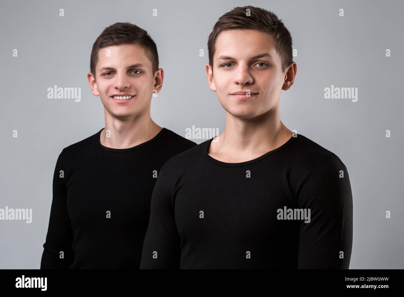 The two twin brother stand on the gray background Stock Photo - Alamy