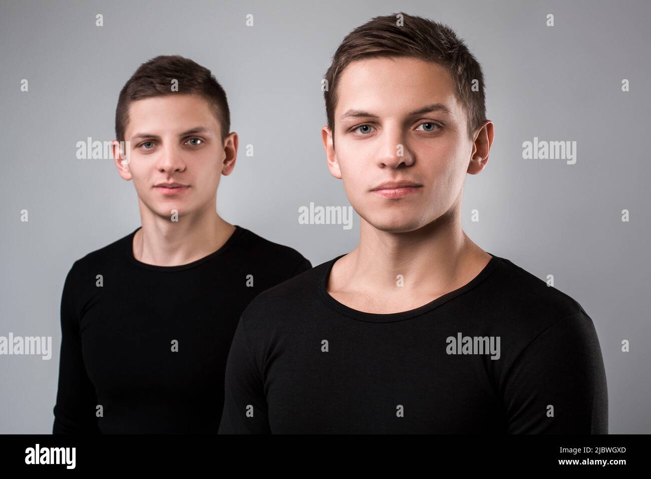 The two twin brother stand on the gray background Stock Photo - Alamy