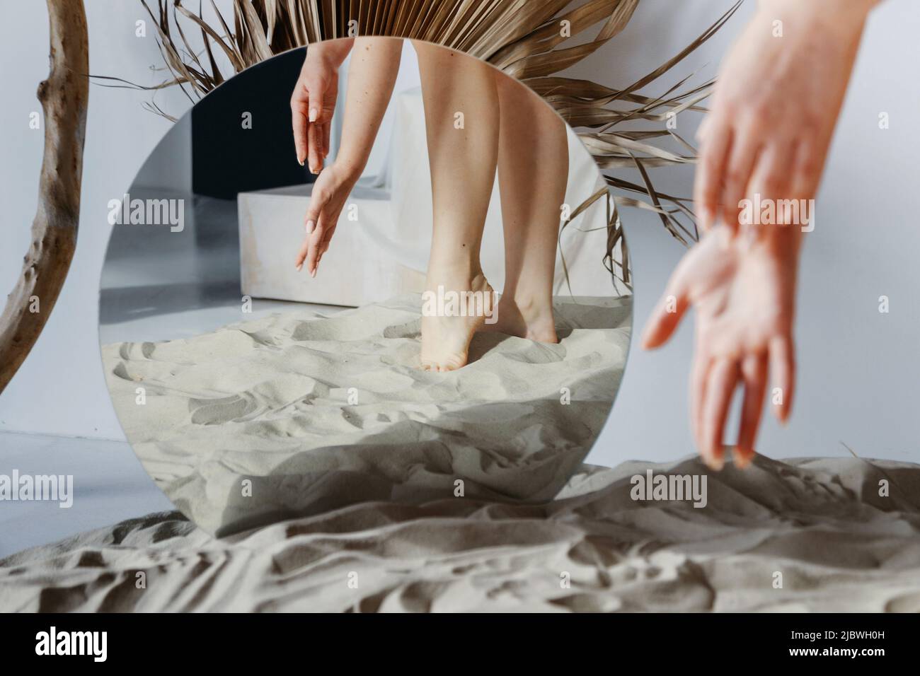 Manicured hands and feet in the mirror reflection. Round mirror in the ...