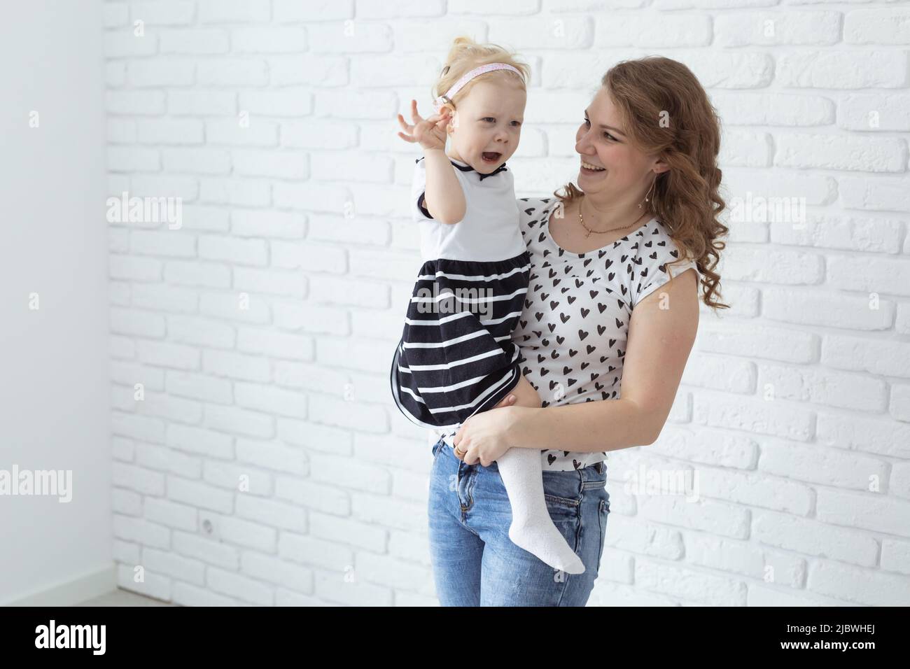 Mother holds and having fun her child with hearing aids and cochlear ...