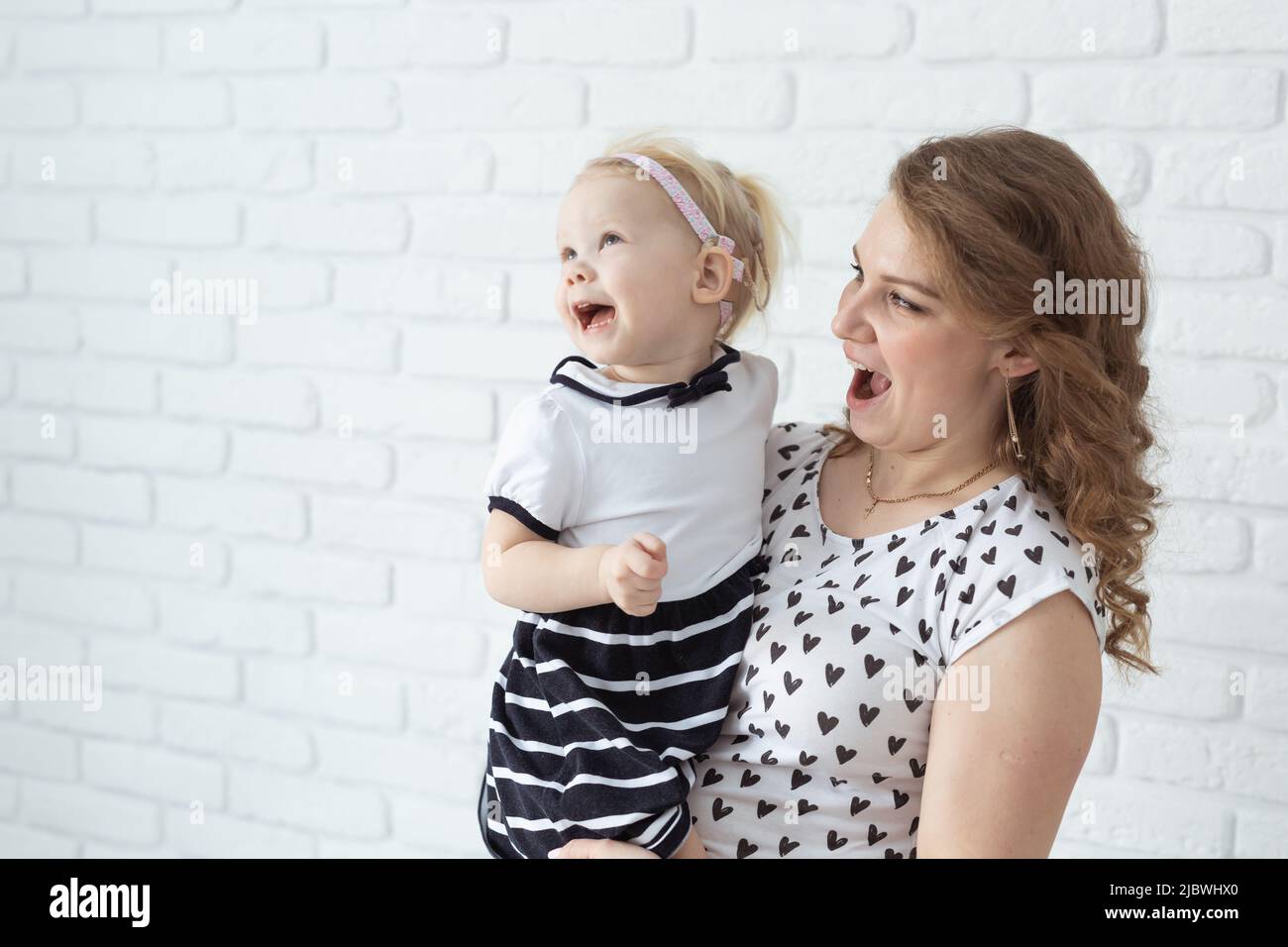 Mother holds and having fun her child with hearing aids and cochlear ...
