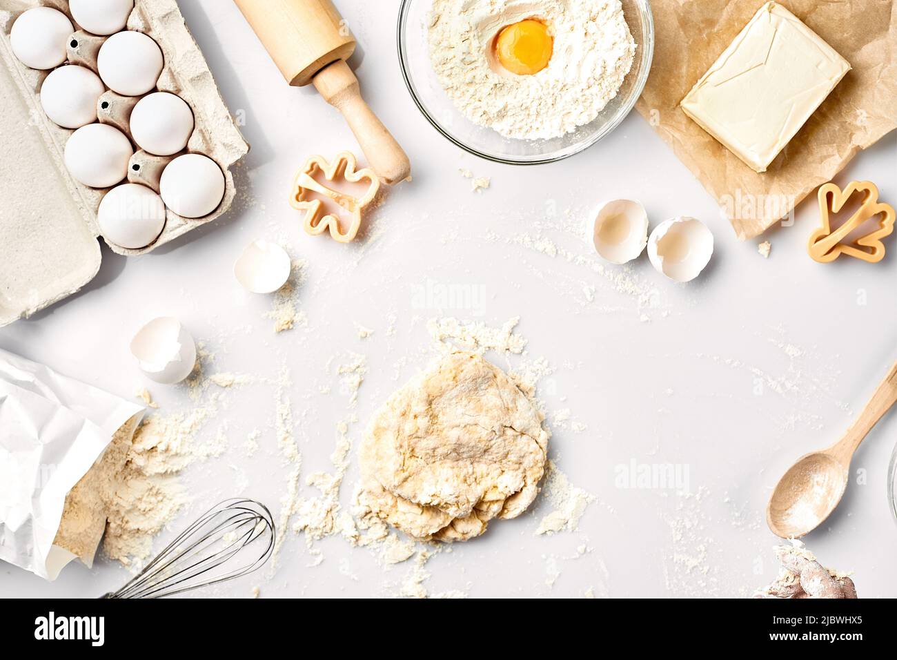 Raw dough ready for kneading on white table. Bakery ingredients, eggs ...