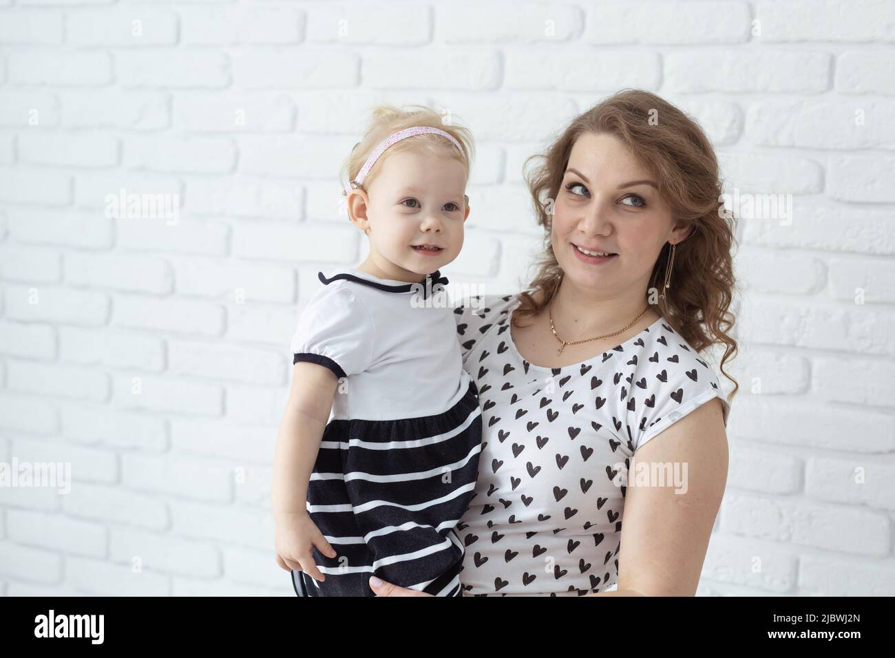 Mother holds and having fun her child with hearing aids and cochlear ...