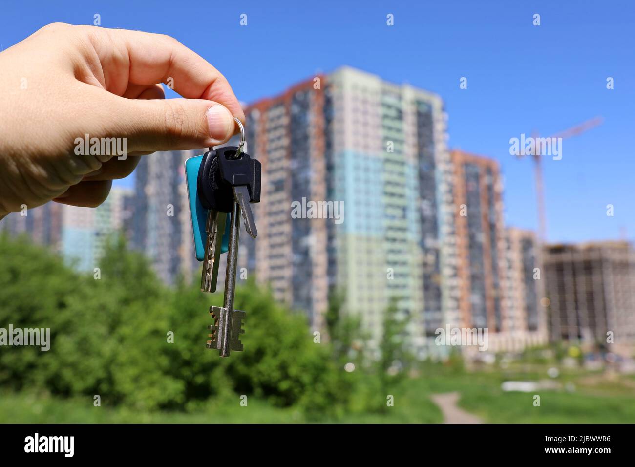 House keys in male hand on background of new buildings, construction ...
