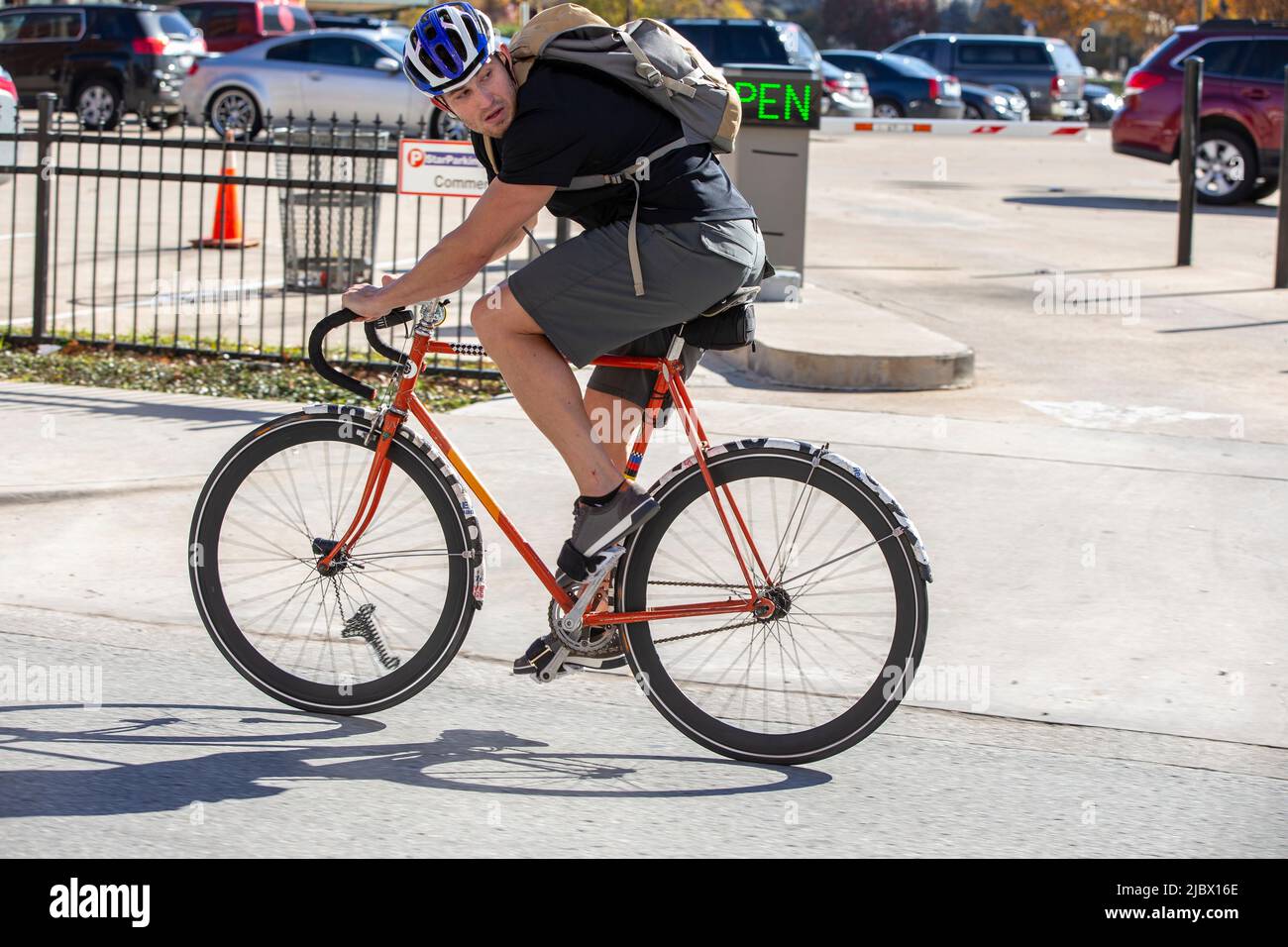 Cyclist looking back over shoulder while biking through city on way to ...