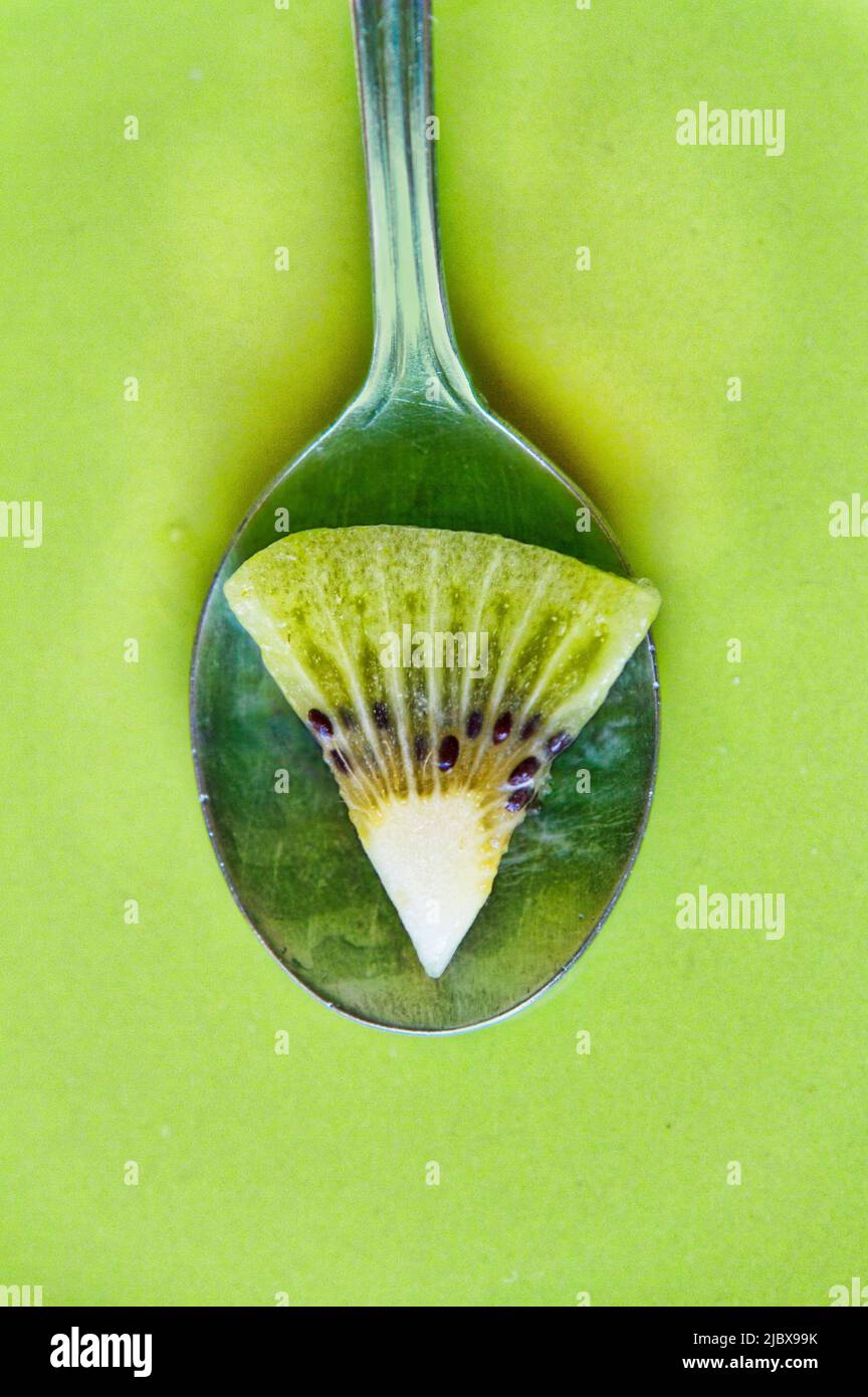 A single bite-sized triangle-shaped slice of kiwi fruit on a silver ...