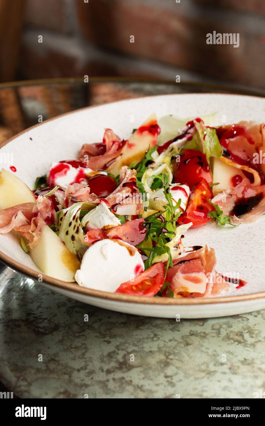 Prosciutto crudo ham salad with mozzarella cheese and arugula on a ...