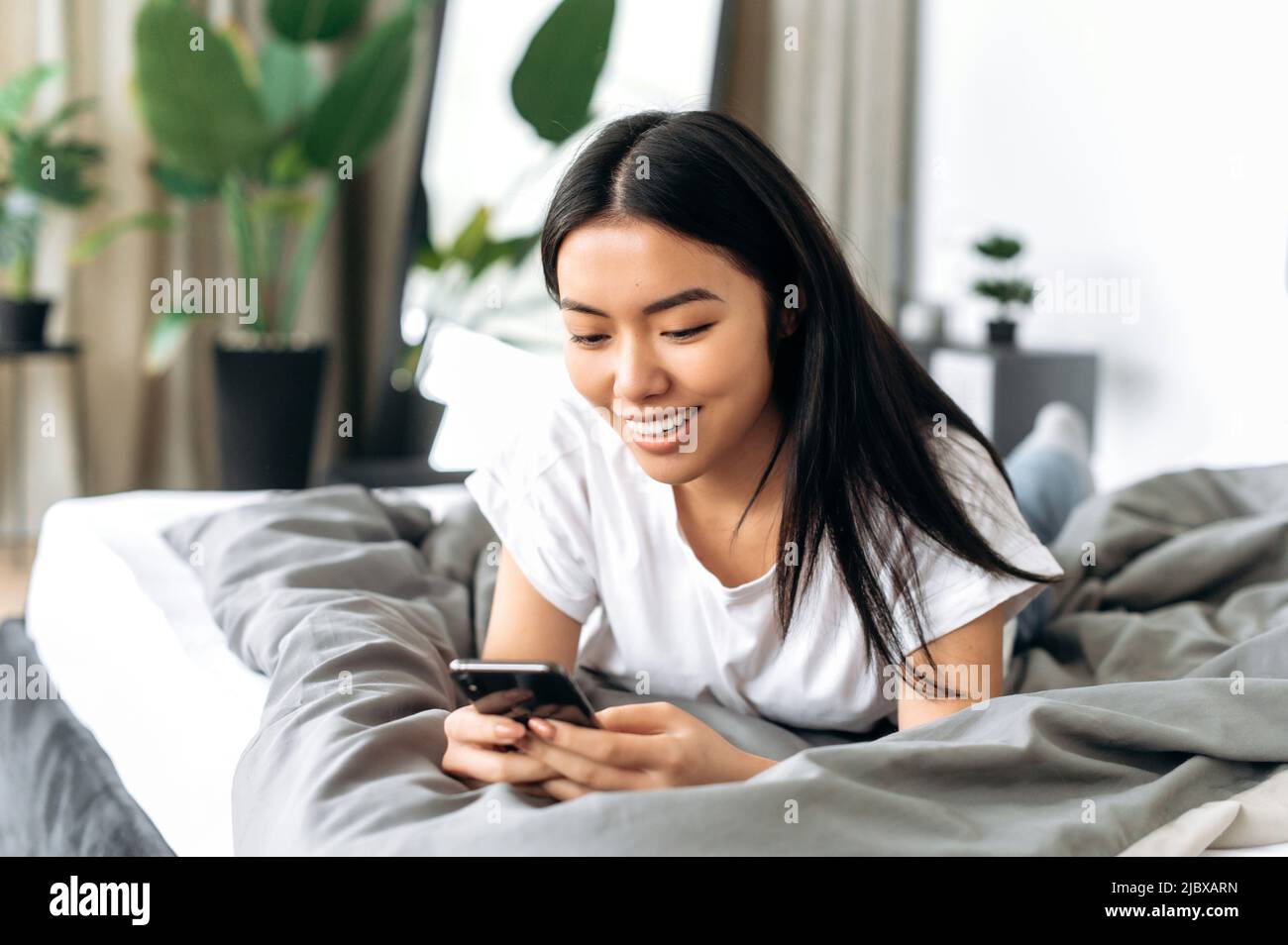 Pretty happy asian brunette girl dressed in a basic white t-shirt, is ...