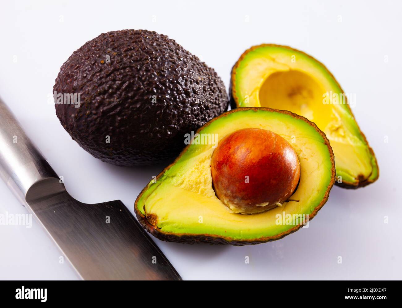 Whole and cut in half Hass avocados on white Stock Photo - Alamy