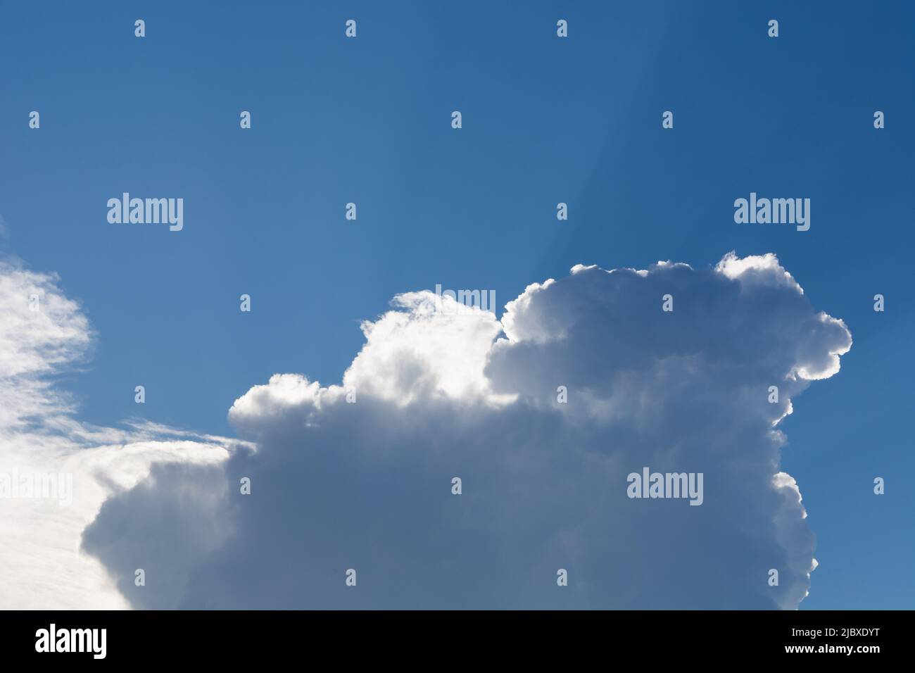 A big rain cloud and the sun rays break through behind the clouds on a ...