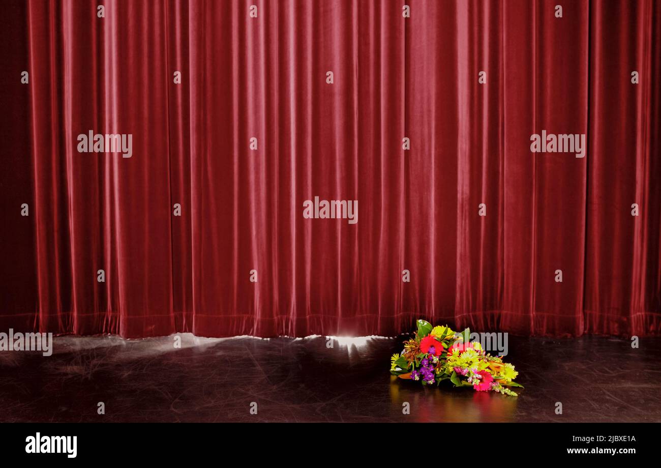 Flowers on stage in front of closed curtain at theatre Stock Photo - Alamy