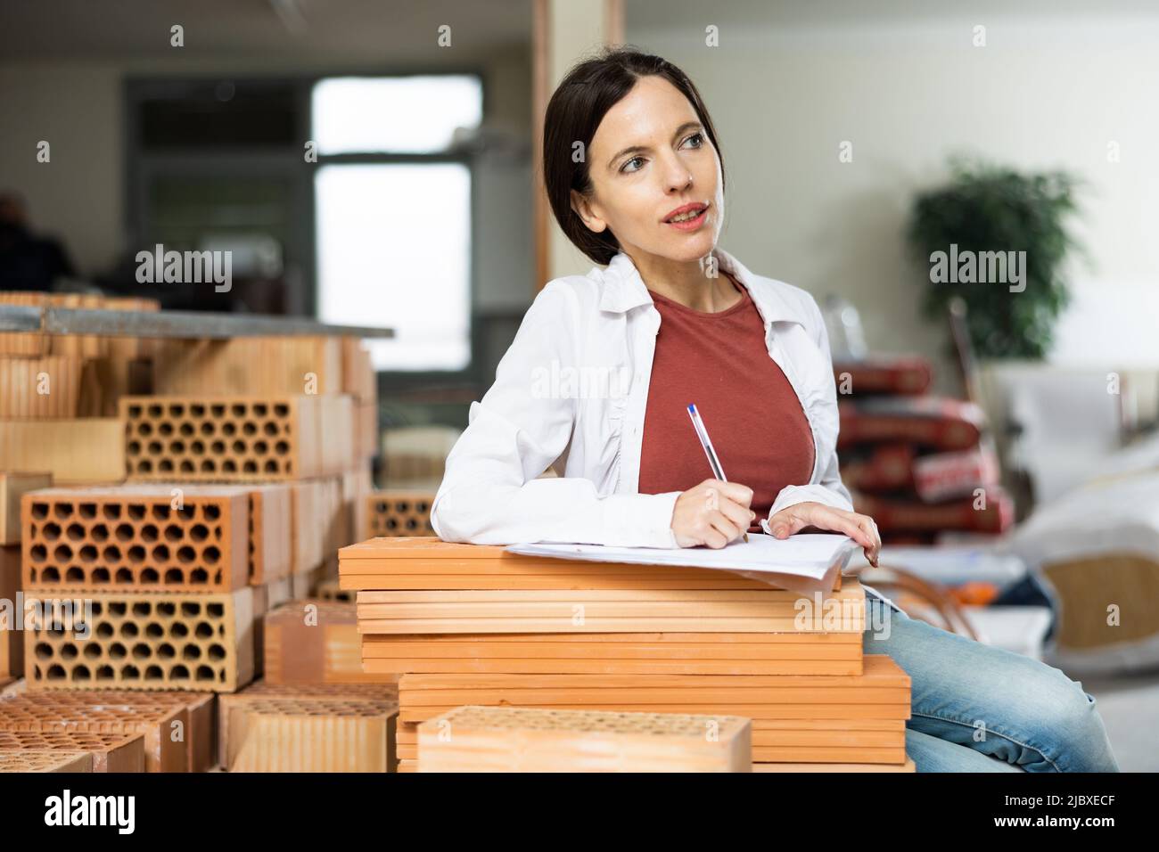 Motivated woman making notes on home space planning during renovation ...