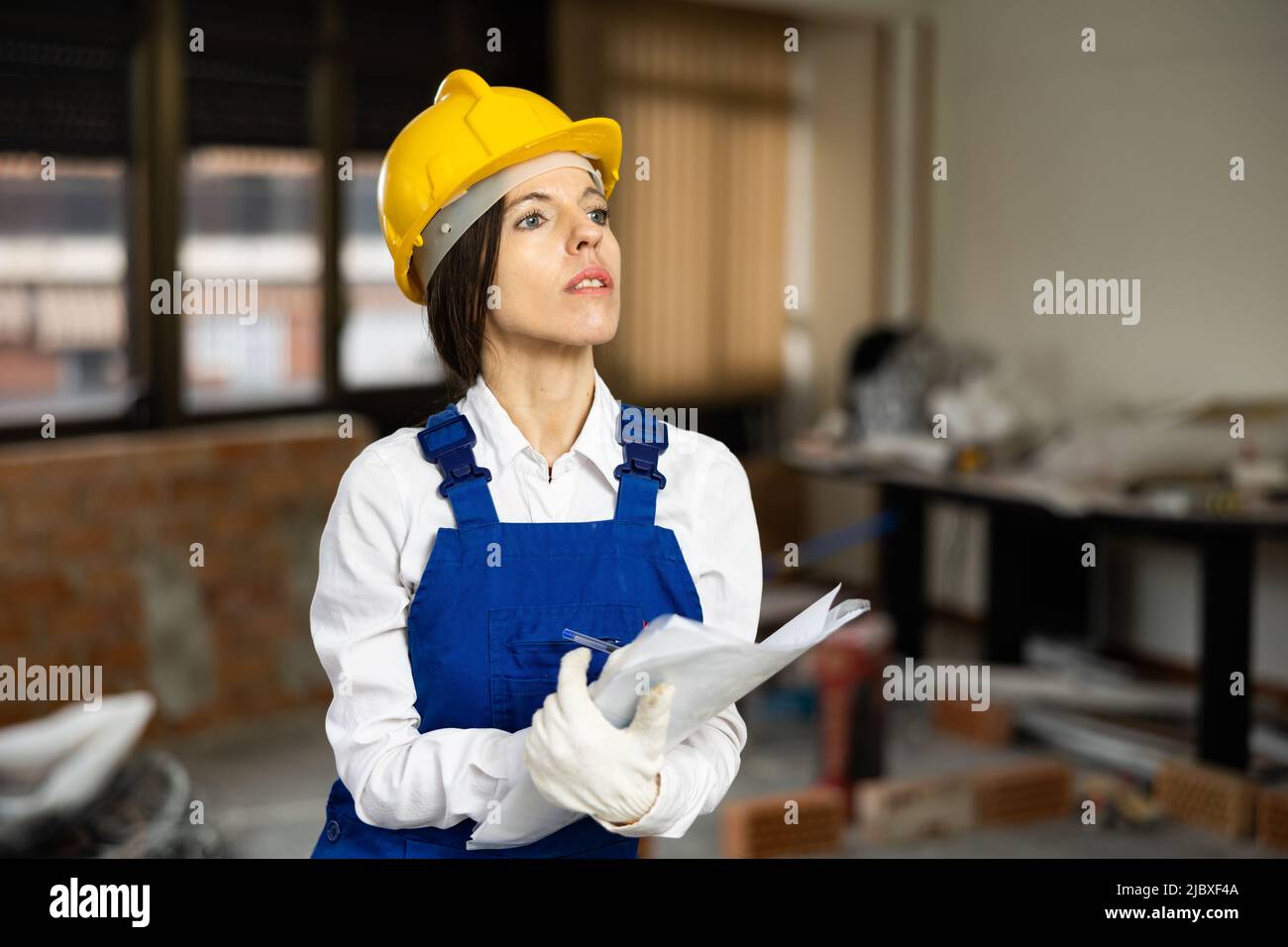 Positive female civil engineer taking notes while checking indoor ...