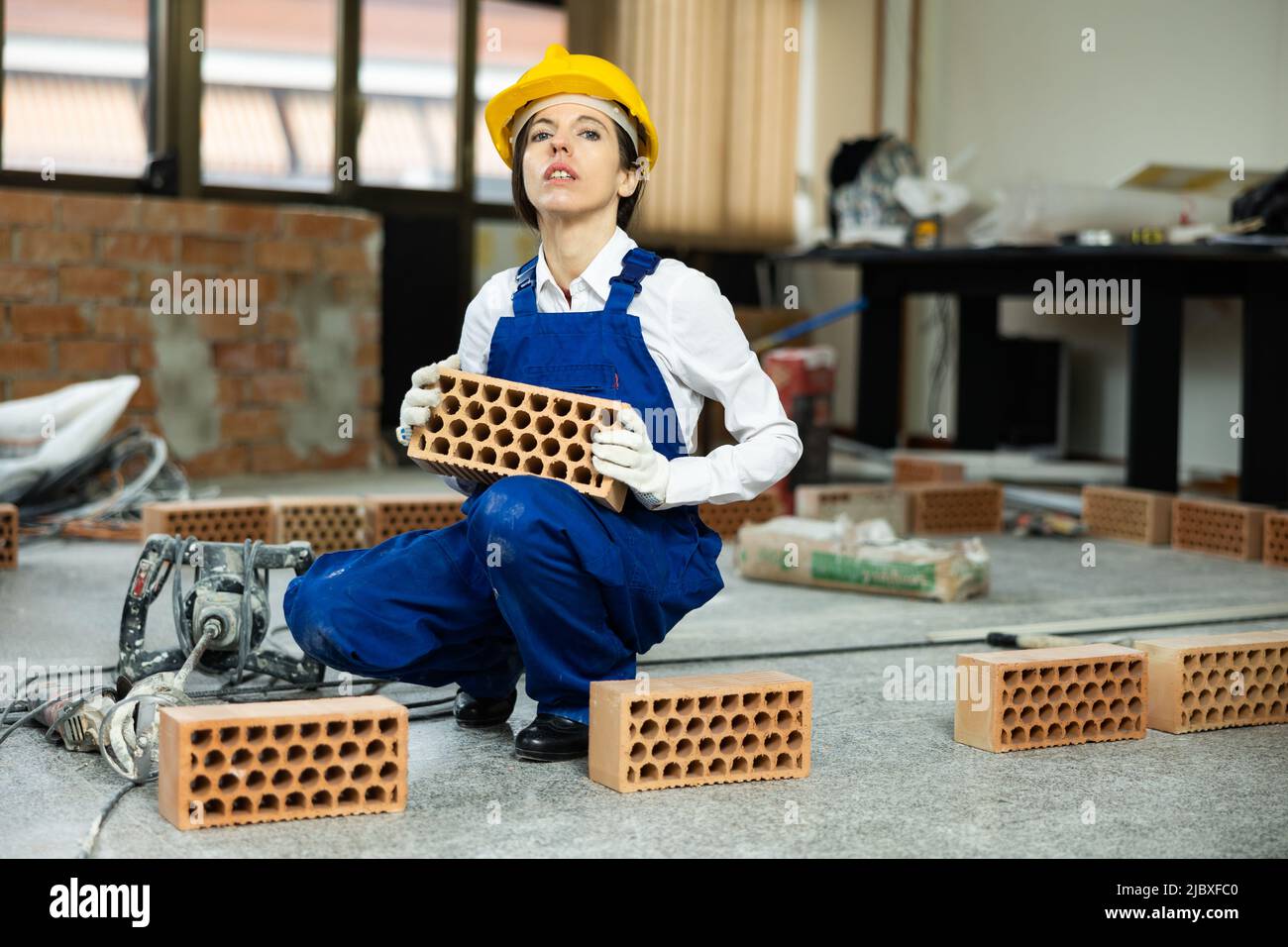 Female builder in safety hard hat preparing bricks for erection of ...